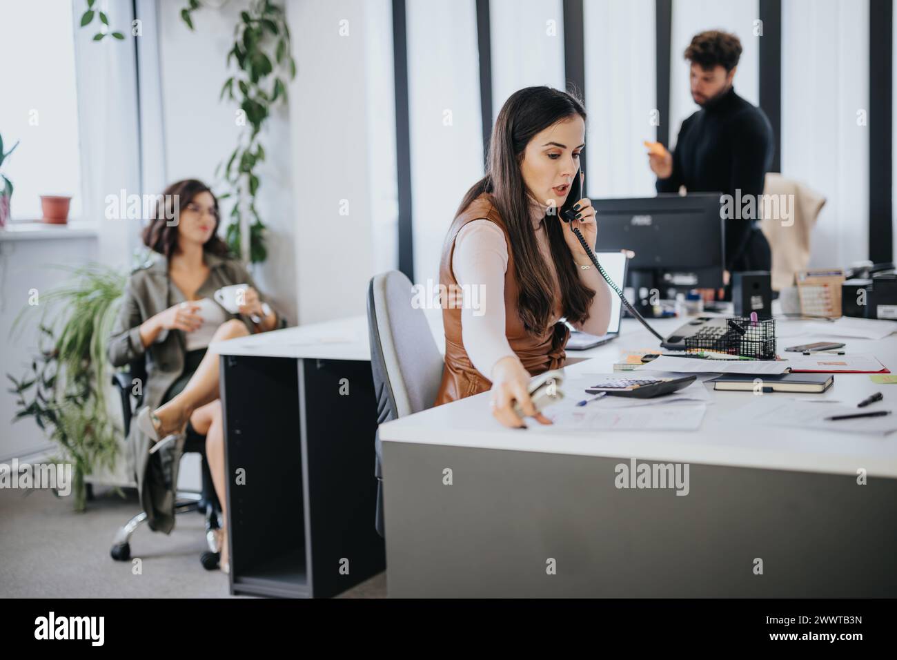 Focused businesswoman on phone handling tasks in busy modern office ...