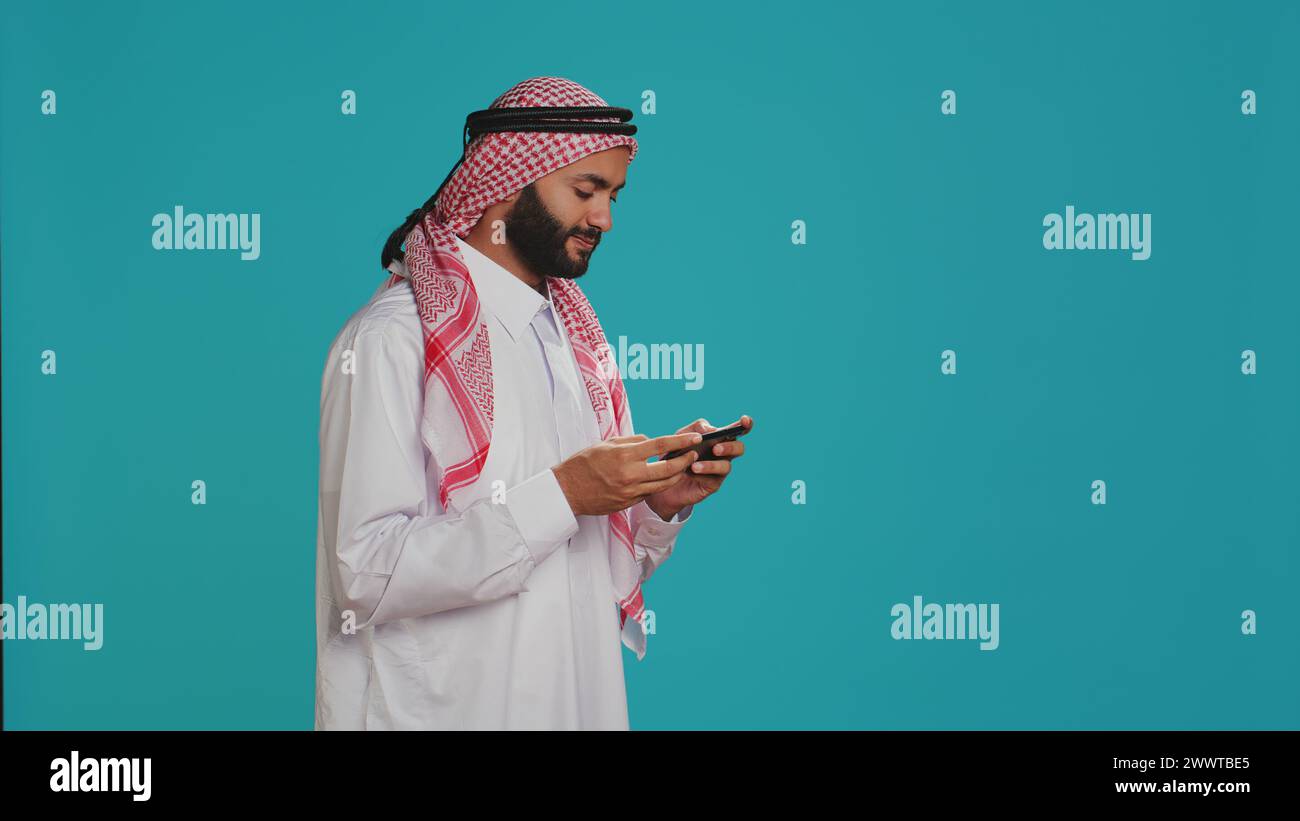 Muslim man wears traditional attire and playing videogames on ...