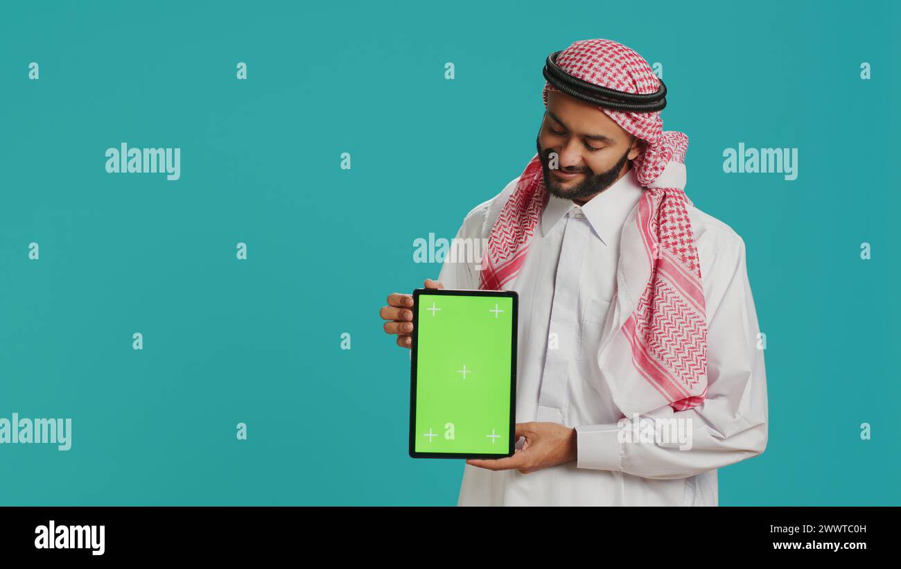 Arab guy presents greenscreen display over studio background ...