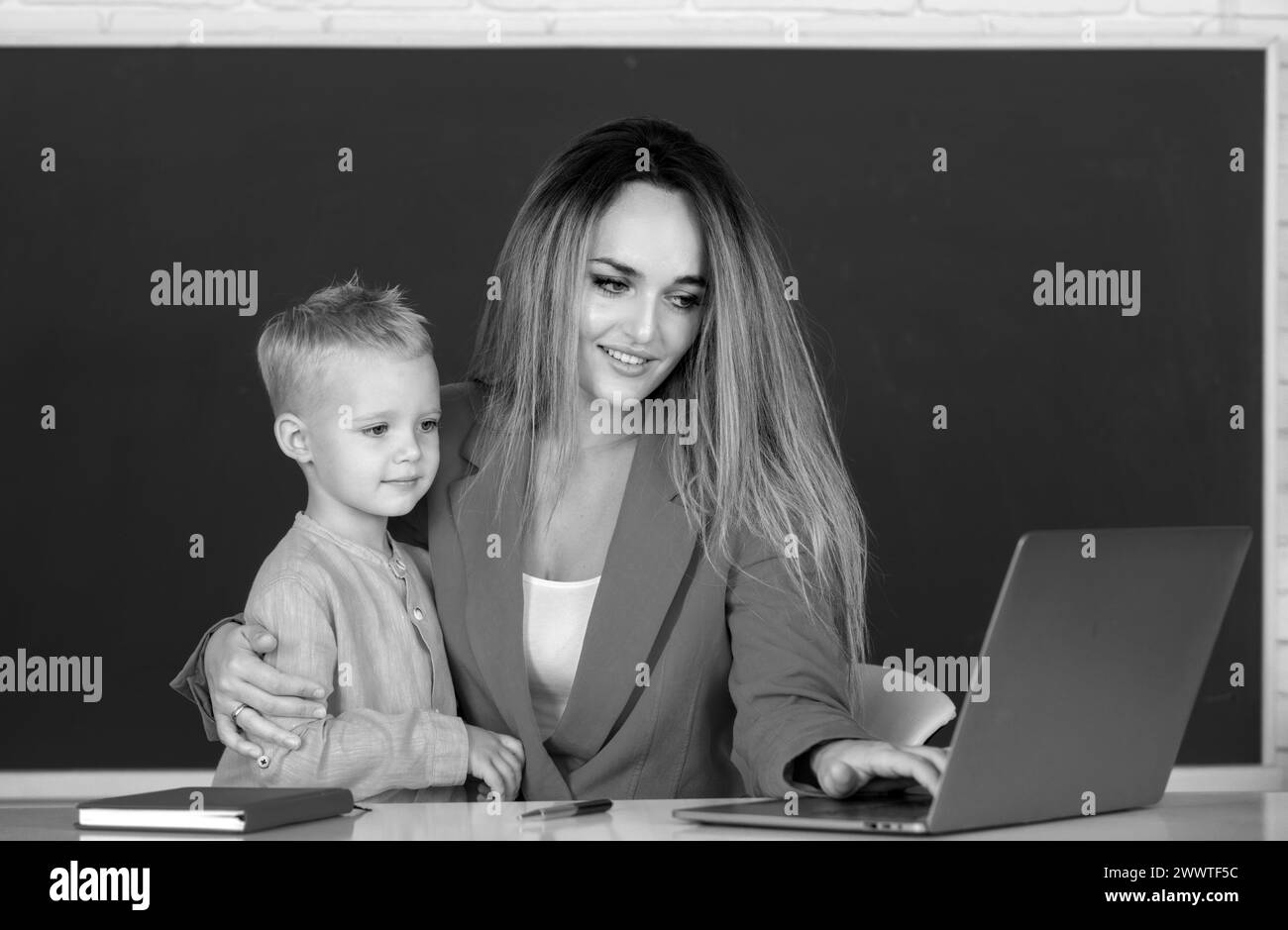 Mother and son together using computer laptop. School child learning ...