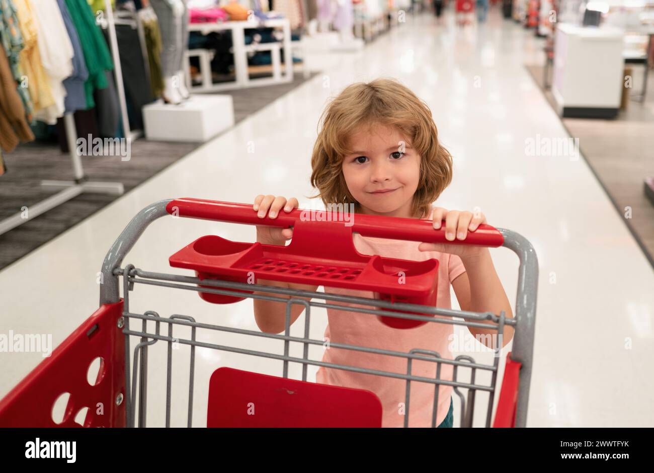 Kid with shopping basket purchasing food in a grocery store. Customers ...
