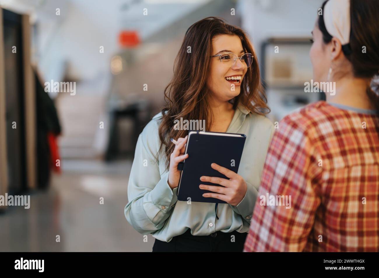 Professional women engaging in a friendly business conversation indoors ...