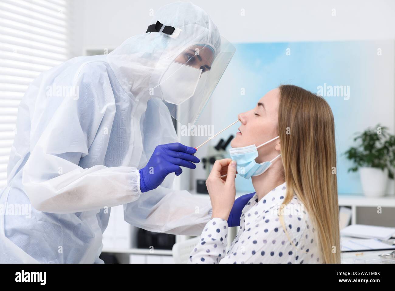 Laboratory testing. Doctor in uniform taking sample from patient's nose ...