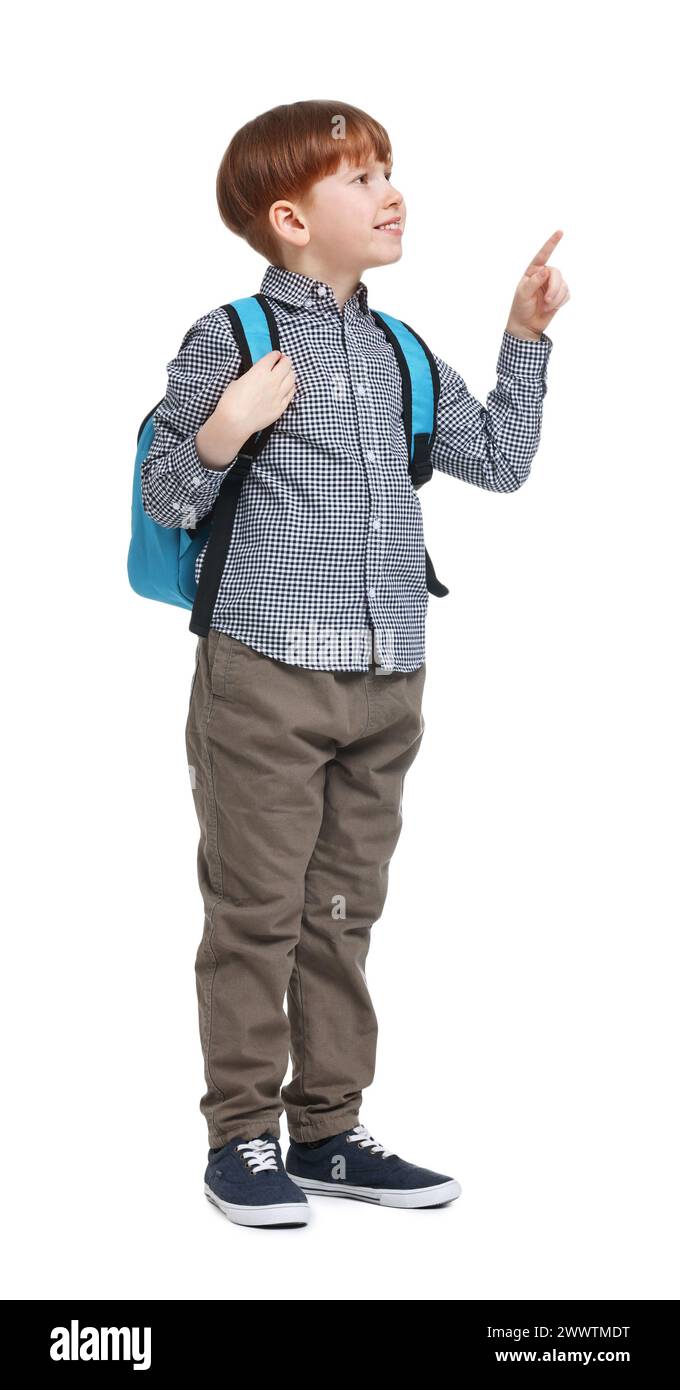 Little boy with backpack pointing at something on white background ...