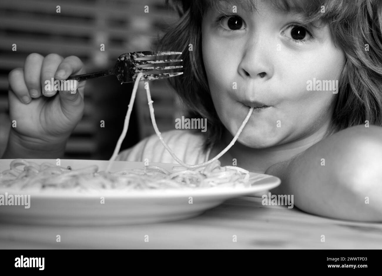 Portrait of a small blond boy eating pasta, spaghetti, closeup. Cute ...