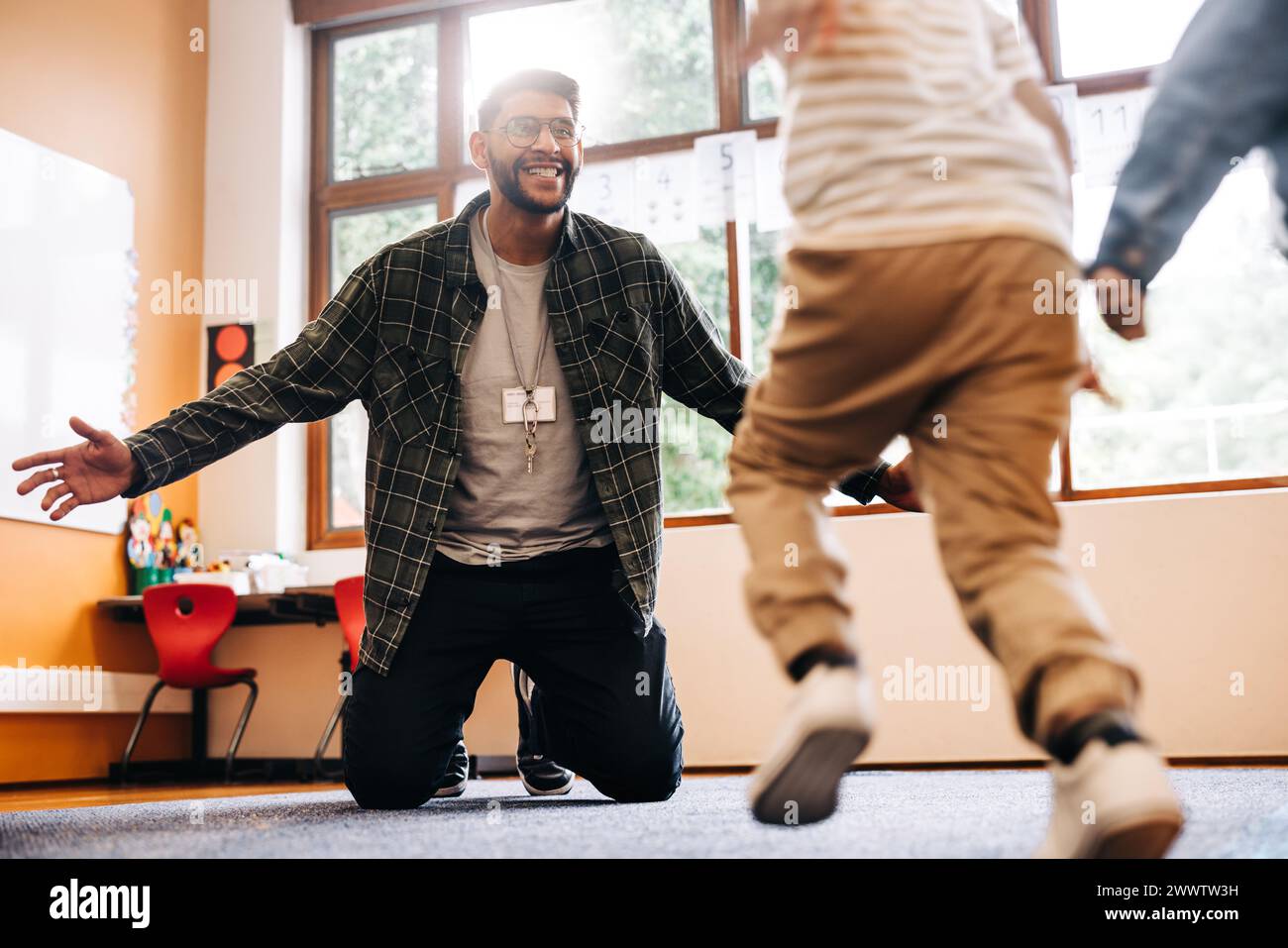 Students running into their teacher’s arms in a primary school. Male ...