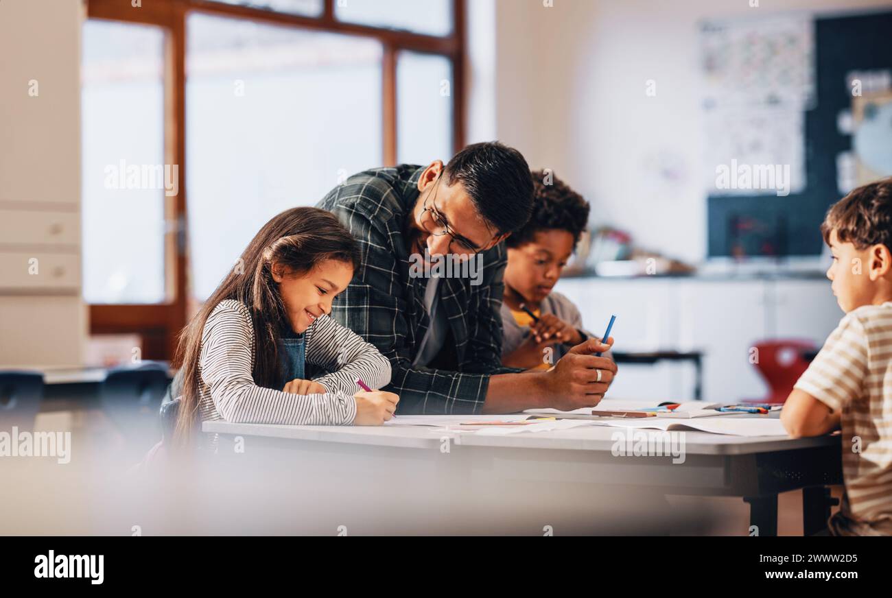 Teacher mentoring primary school children in a class. Male educator ...