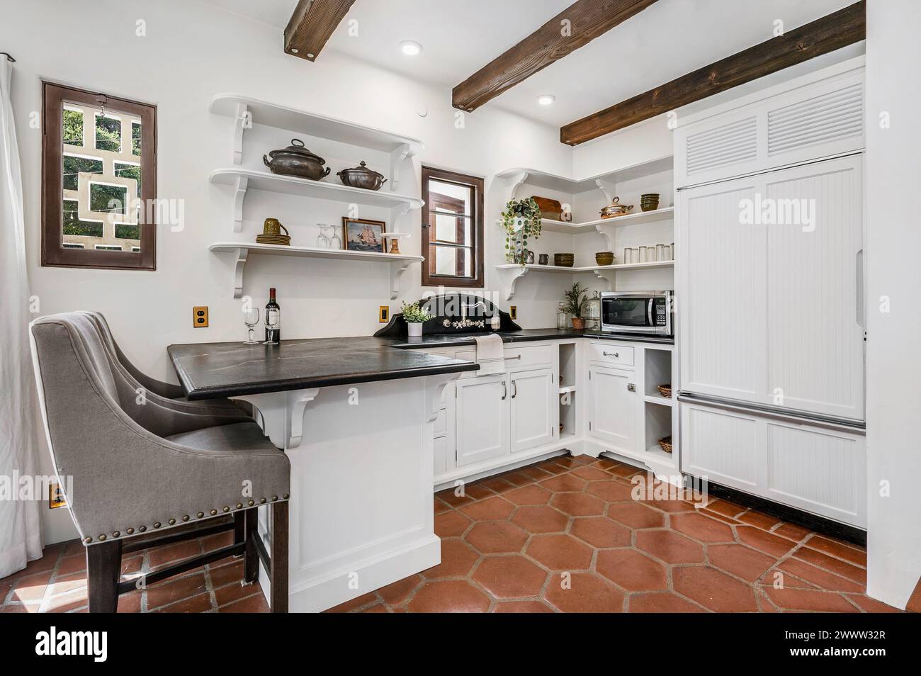 A kitchen equipped with stove, refrigerator, sink, and chairs Stock ...