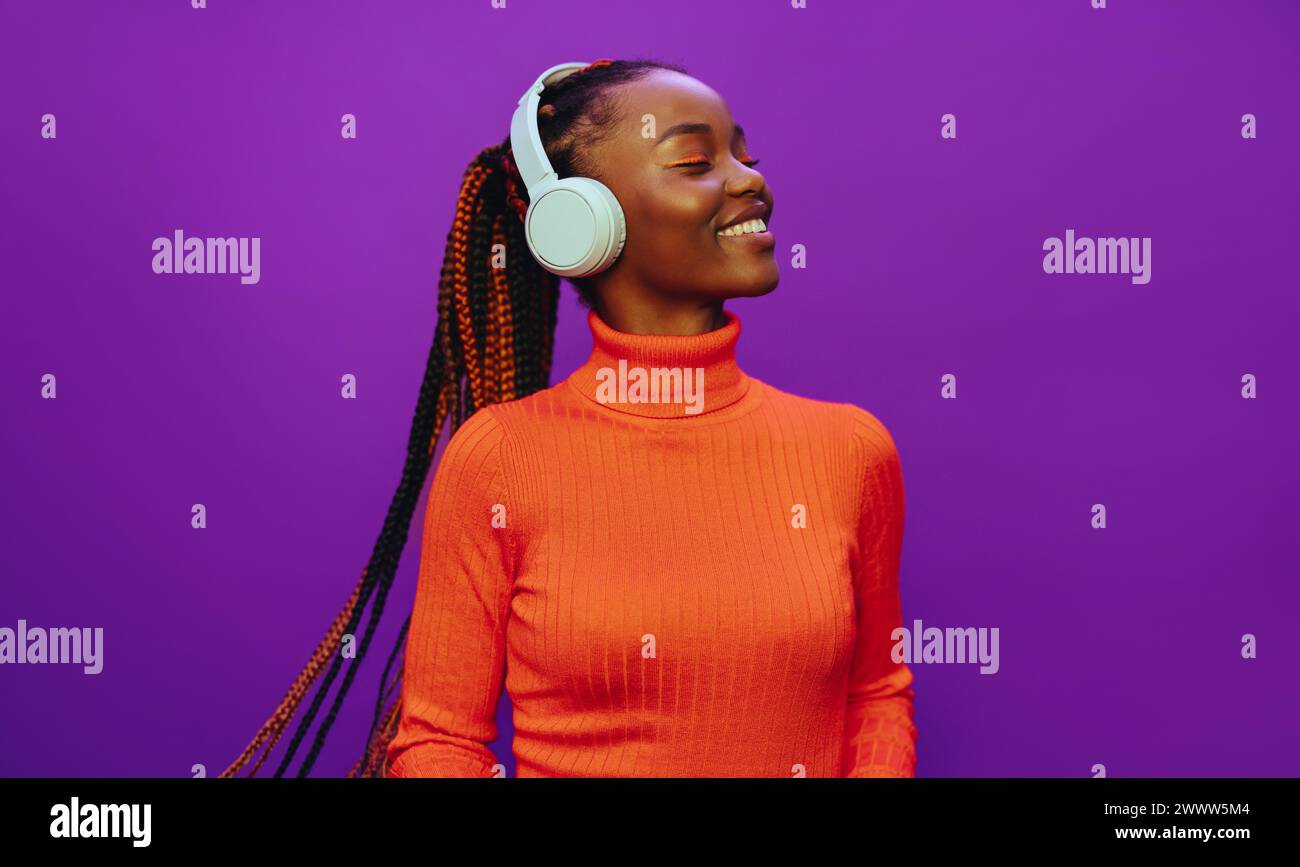 Cheerful young woman with vibrant two-tone braids stands against a ...