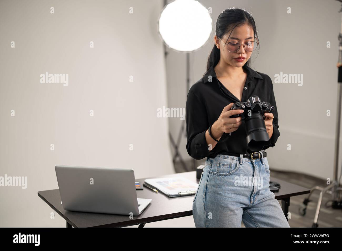 A professional Asian female photographer is focusing on adjusting her ...