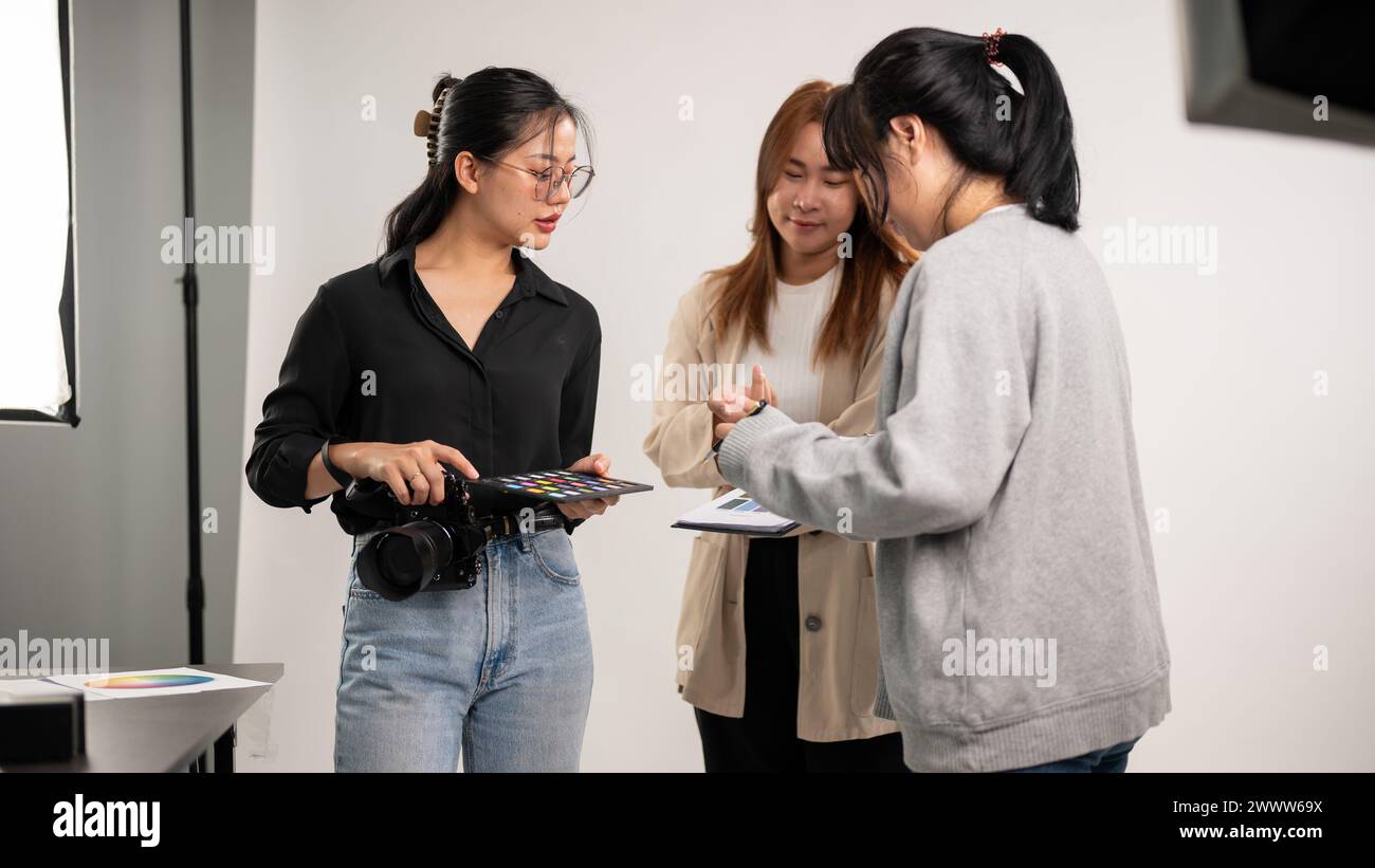 A professional Asian female photographer talking with an art director ...