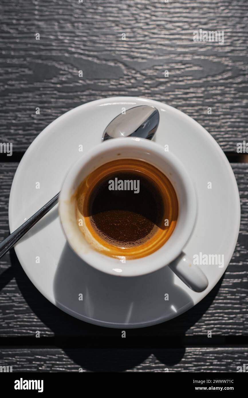 White cup with espresso on a black table in a street cafe, top view ...