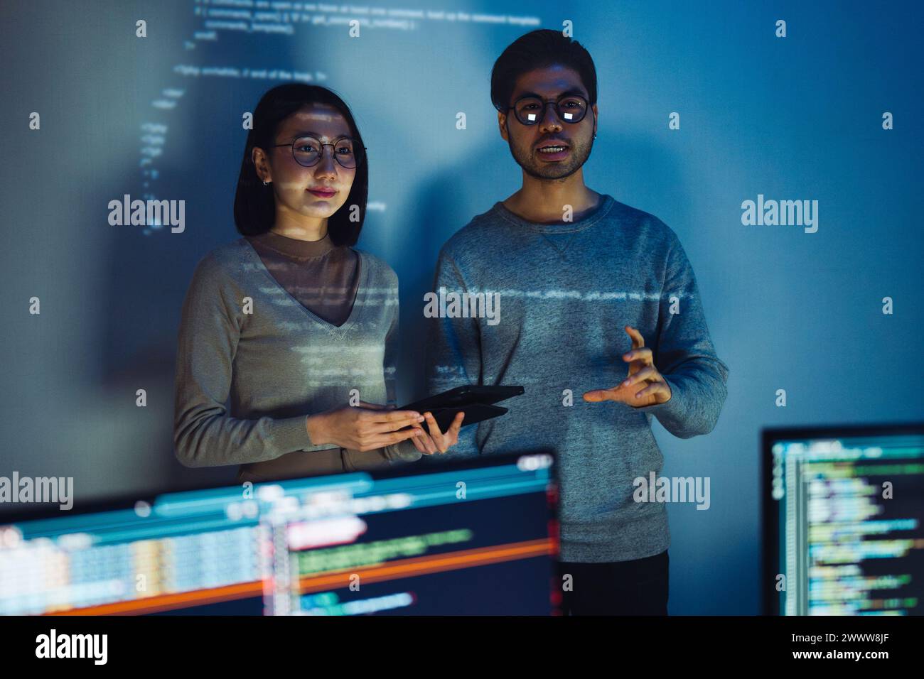 Two Asian And Indian Developer Presentation About Coding Software Data With Devops Team At Night