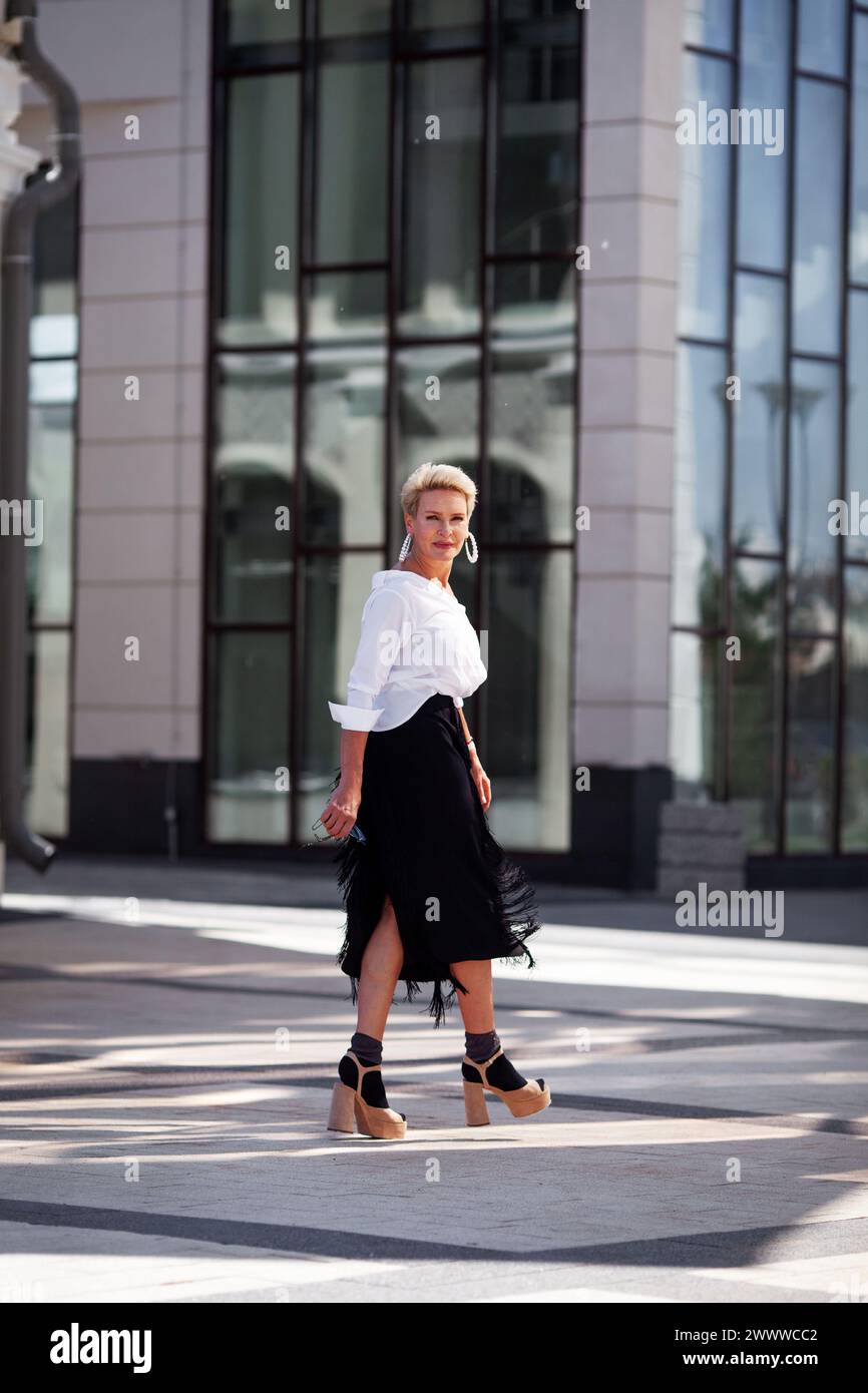 Stylish middle aged fashionista, dressed in trendy attire black skirt ...