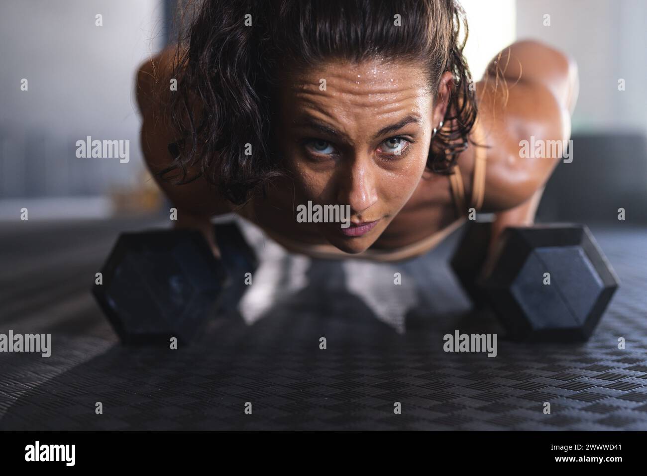 A fit Caucasian woman is doing push-ups with dumbbells in the gym Stock ...