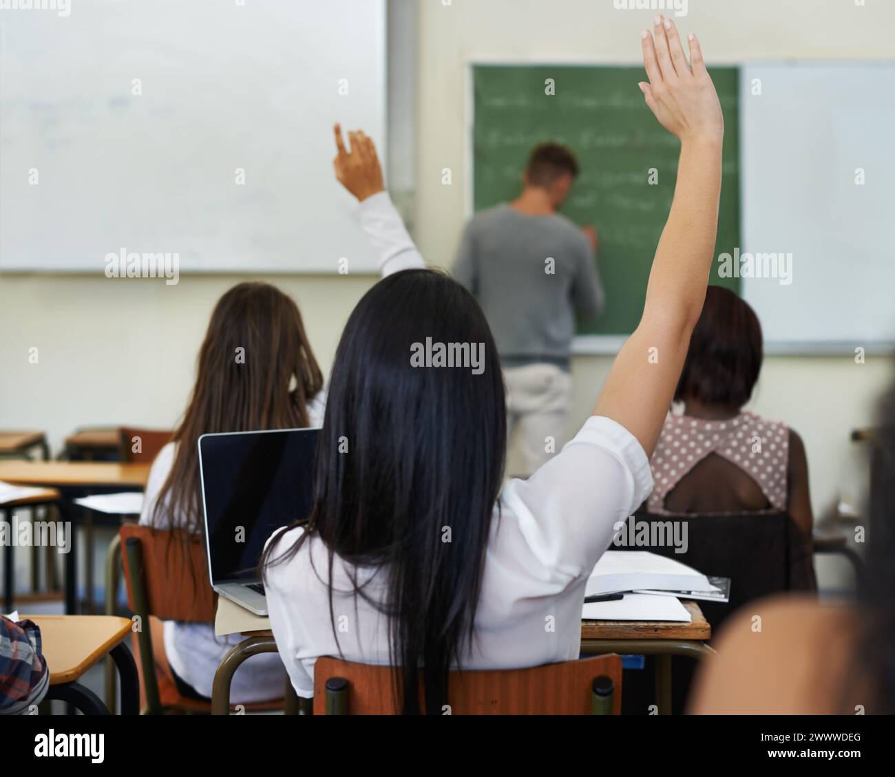Students, question and hands up to lecturer in classroom, lesson and ...