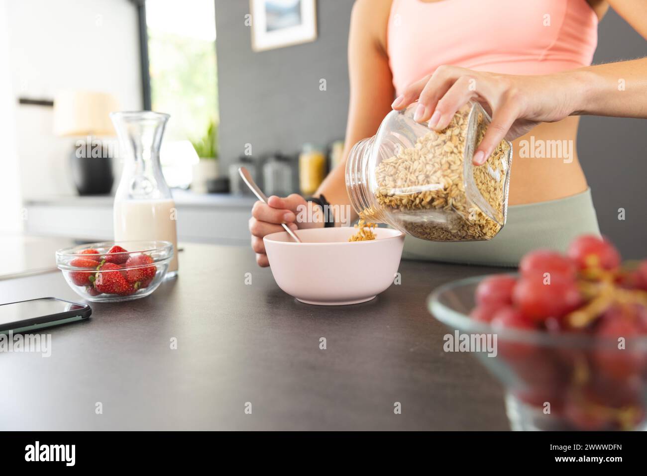 A woman is pouring cereal into a bowl for breakfast Stock Photo - Alamy