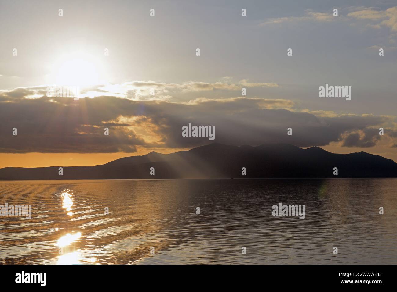 SUN RAYS PEERING THROUGH THE CLOUDS ABOVE THE ISLE OF ARRAN ONTO THE ...