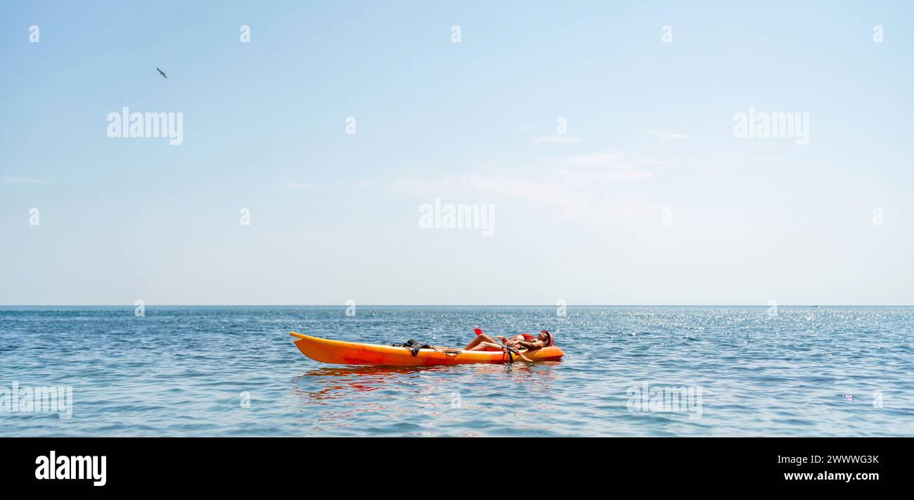 Kayak sea woman. Happy attractive woman with long hair in red swimsuit ...