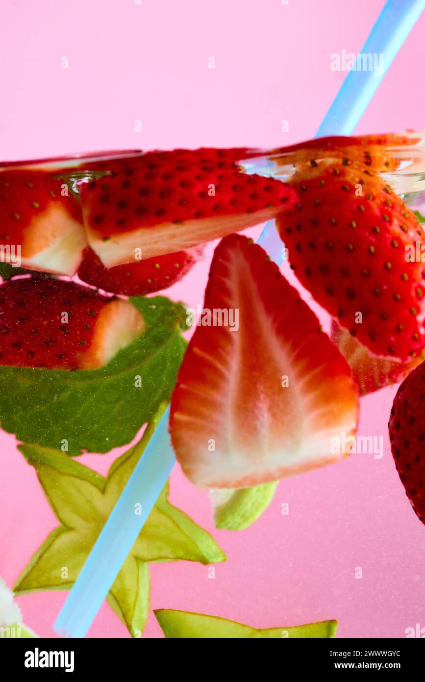 Sliced strawberries, carambola and green leaves floating in water with ...