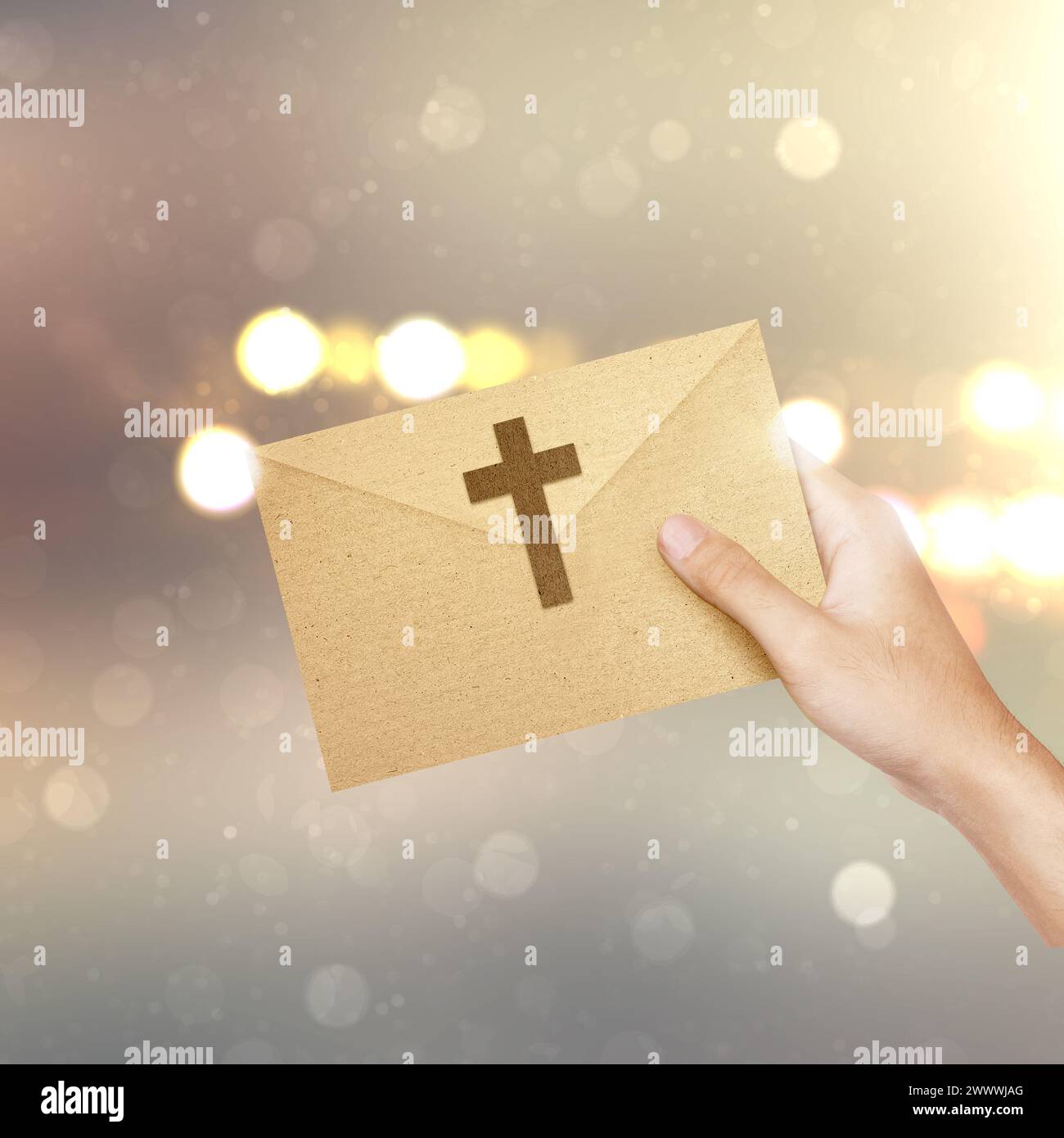 A human hand holding a letter with a Christian cross symbol with a ...