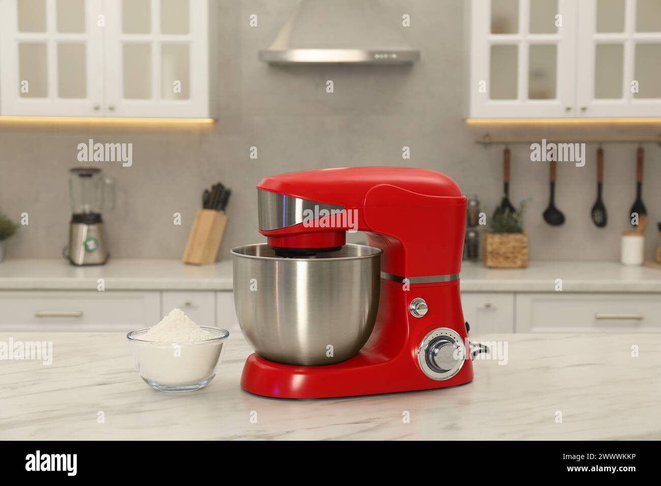 Modern red stand mixer and bowl with flour on white marble table in ...