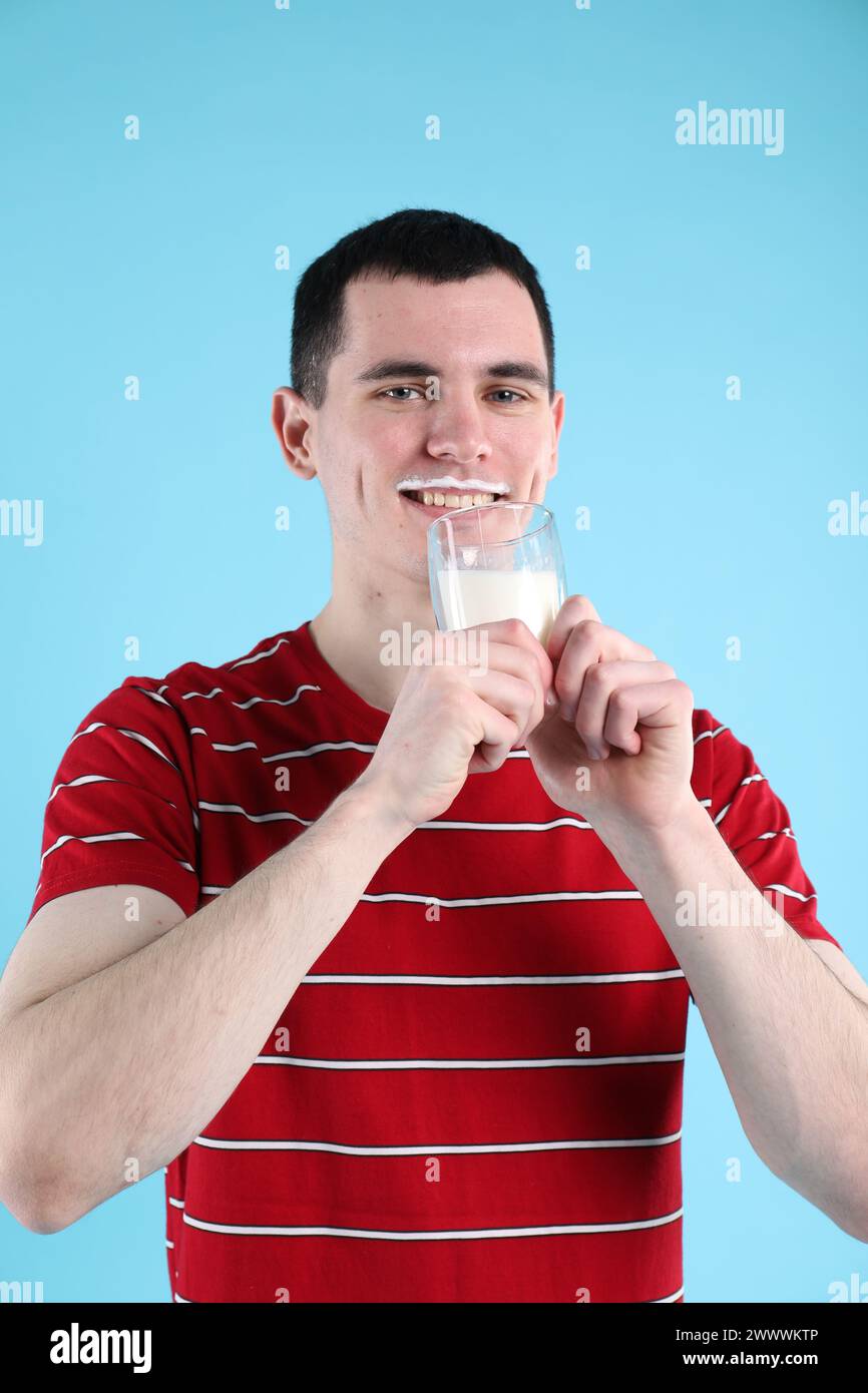 Milk mustache left after dairy product. Man drinking milk on light blue ...