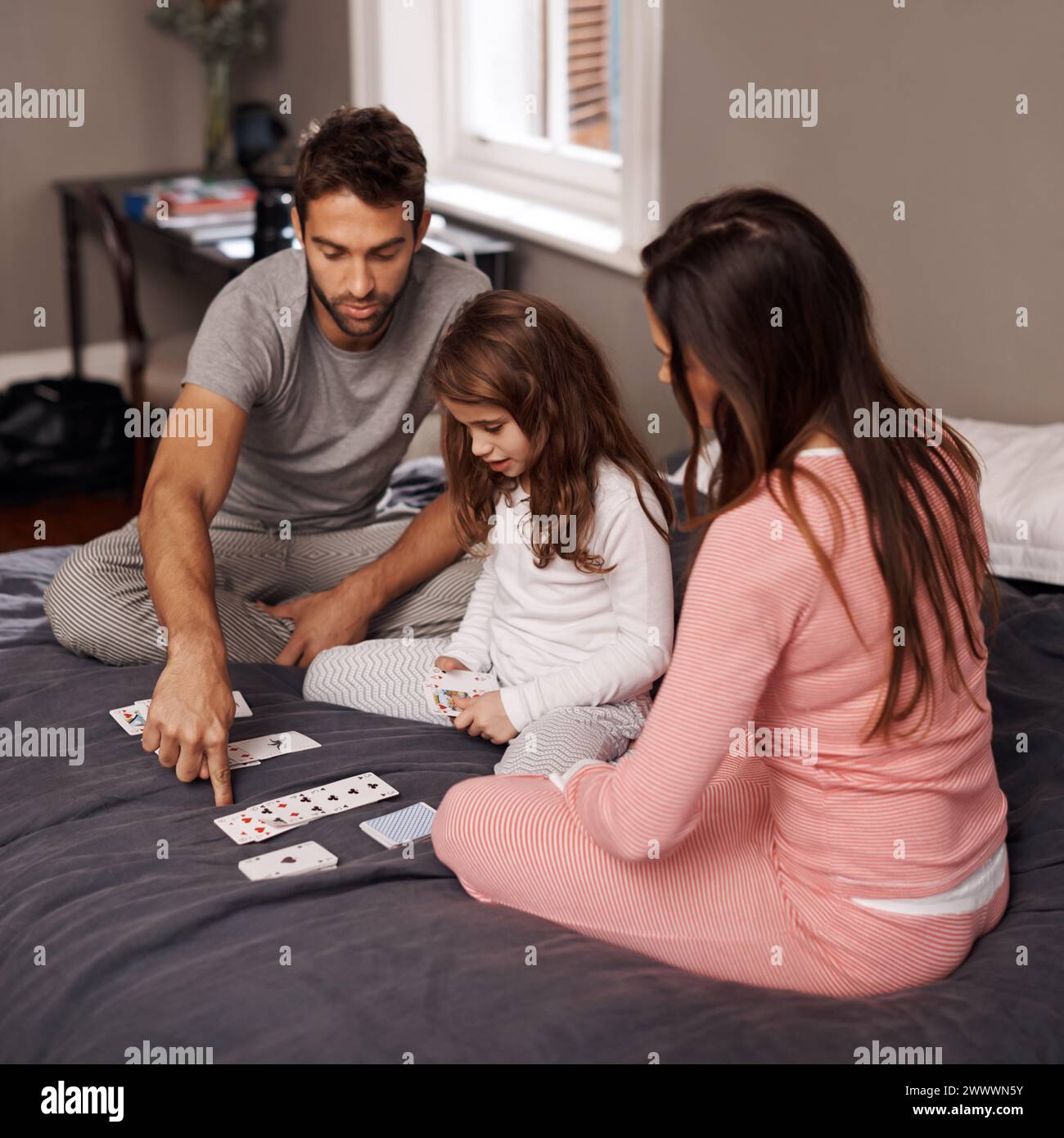 Parents, girl and playing cards to relax for fun with bonding, learning ...