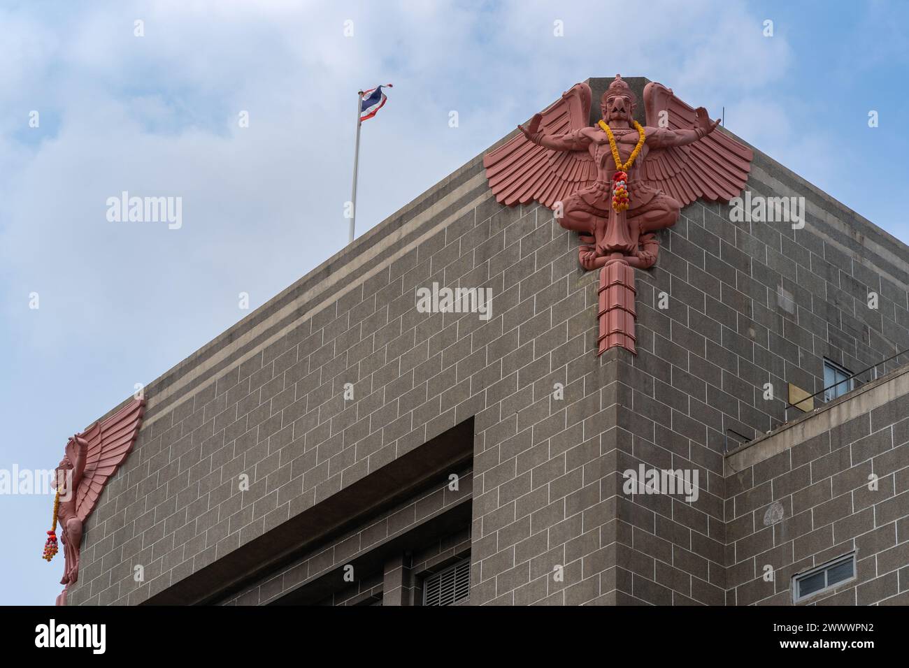 Horizontal view of garuda or khrut reliefs and thai flag on facade and ...