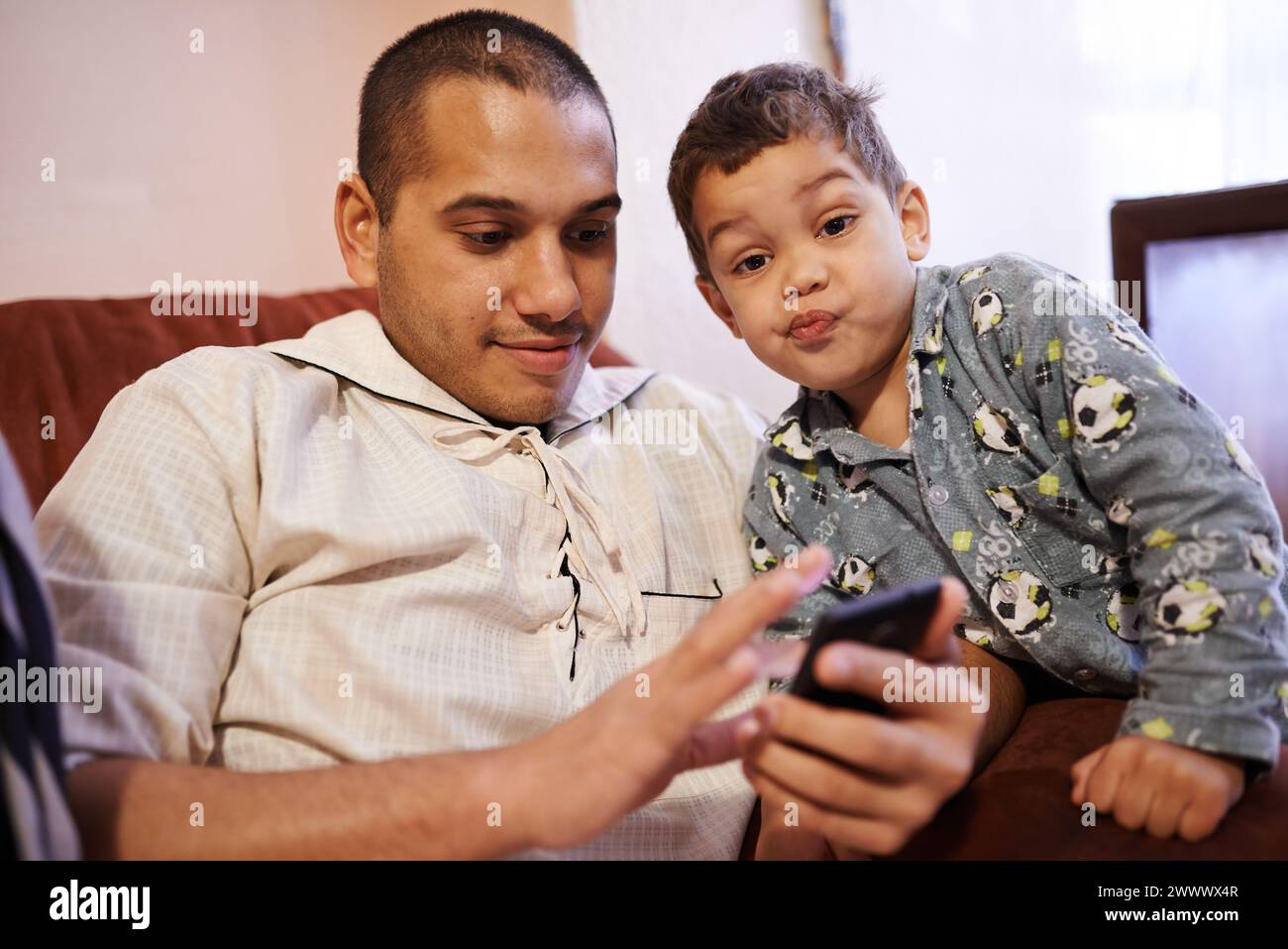 Child, muslim father and smartphone in home for playing games, bingo or communication with ...
