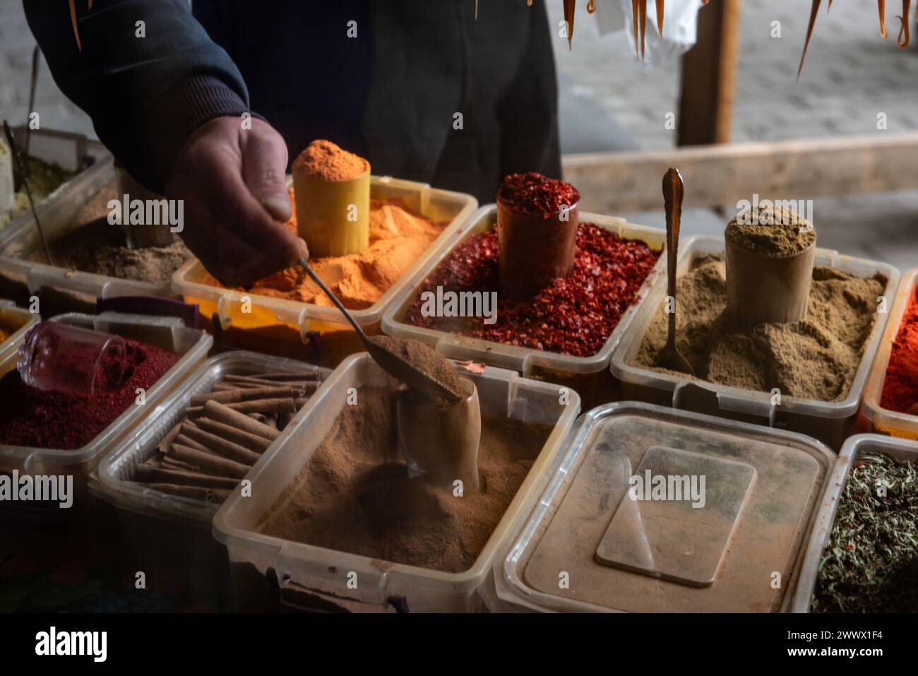 A man scoops freshly ground spices for a customer at an outdoor food ...