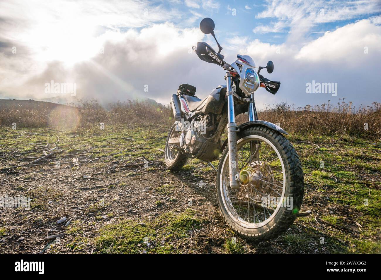 Ein Enduro Motorrad steht auf einem Feldweg der durch die Landschaft ...