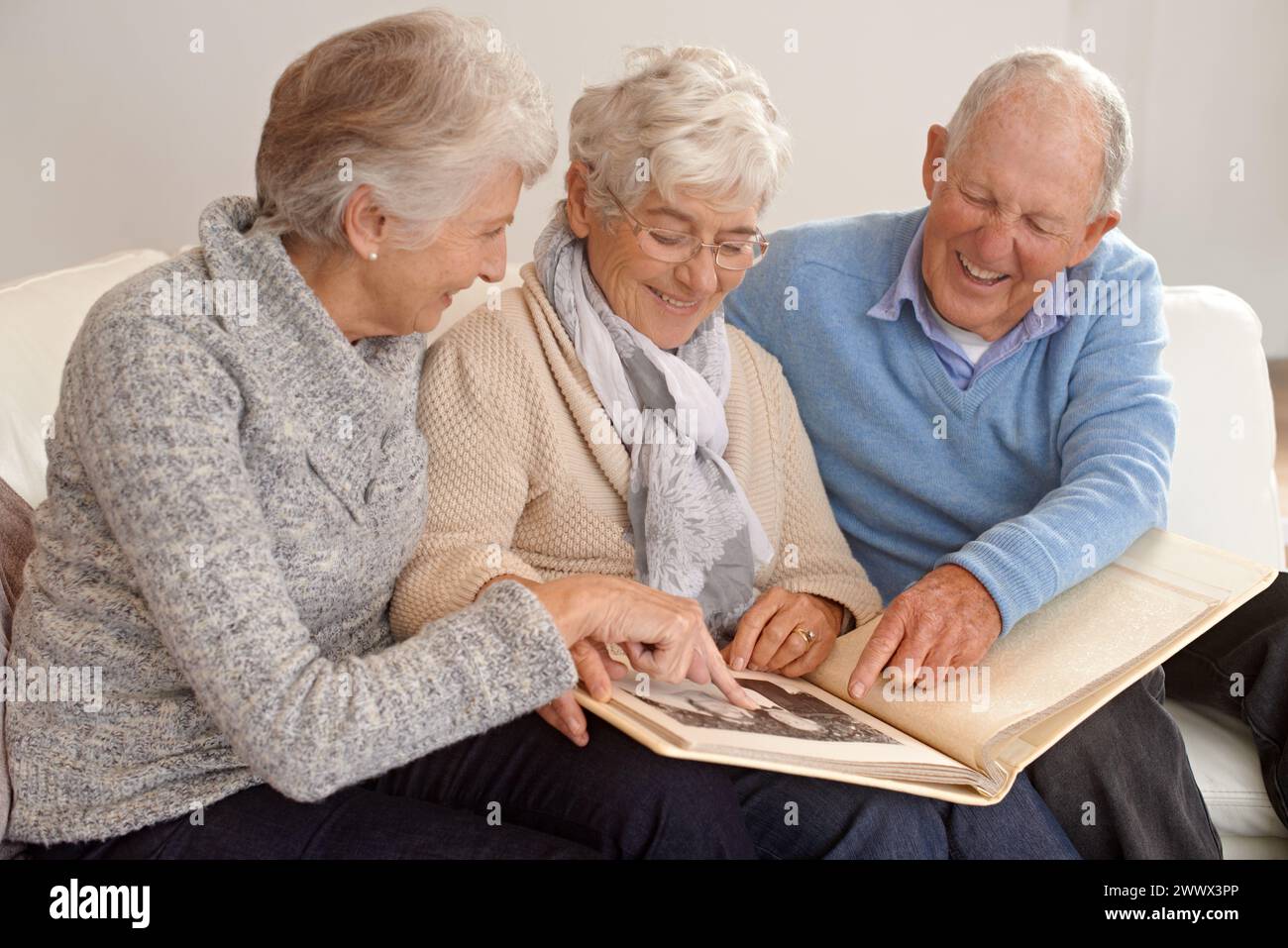 Elderly people, group and together with photo album, living room and ...