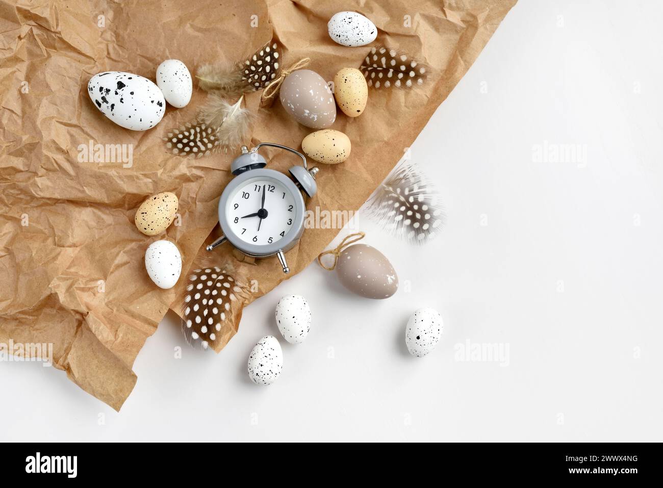 Easter eggs with clock and feathers on a brown kraft paper background ...
