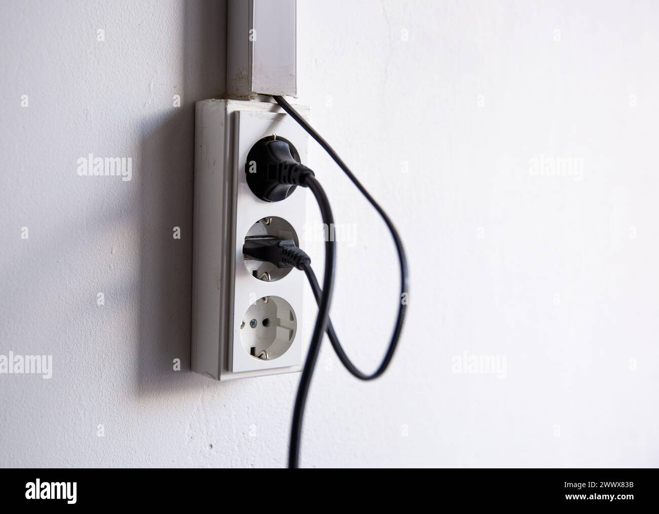 Close up of a socket and plugs on white wall, bad electricity at home ...