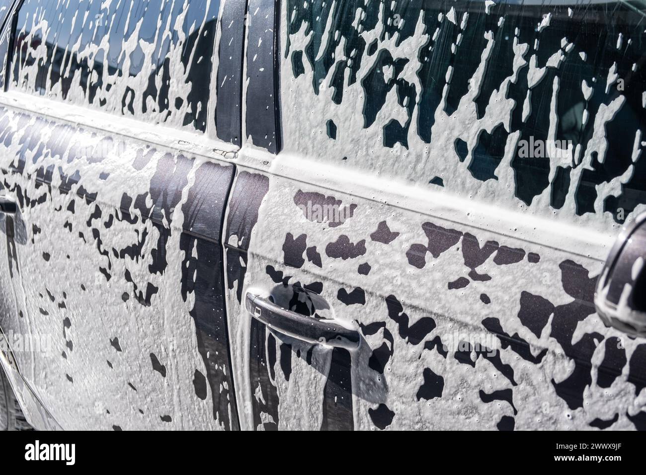 Foamy car at car wash, with tire, wheel, and hood covered in suds Stock ...
