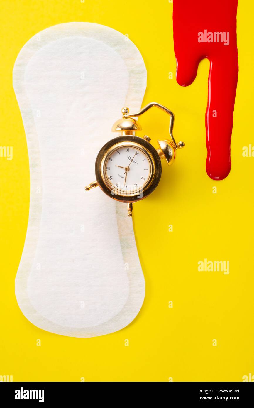 Blood, alarm clock and feminine hygiene pad with red glitter on yellow ...