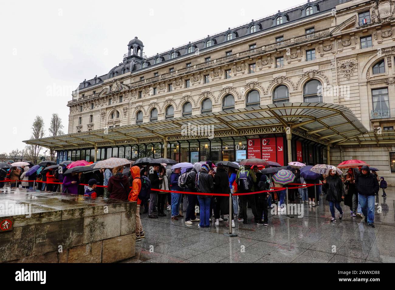 Paris, France. March 26, 2024. Visitors stand in line, in the rain ...