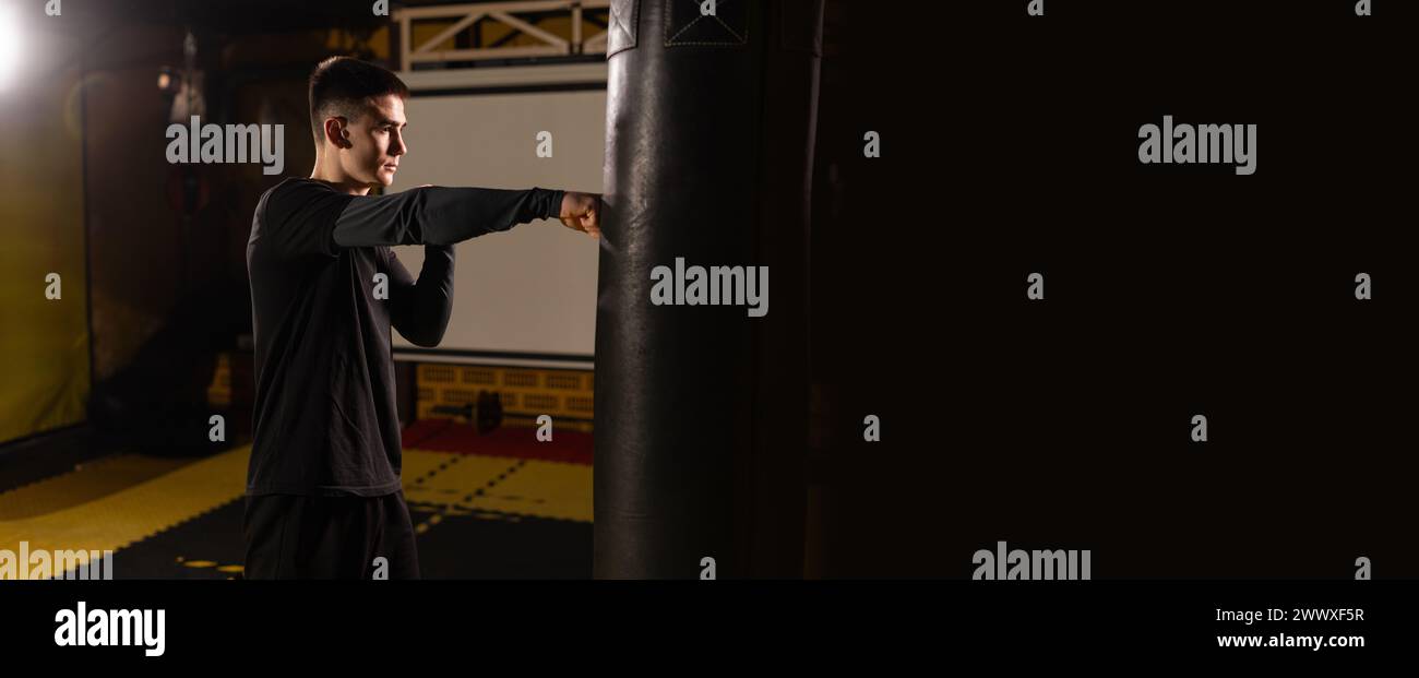 male young boxer hitting a punching bag at a boxing club. Handsome man boxer training hard Stock ...