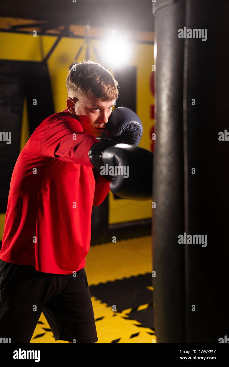 Young boxing male athlete punching boxing bag while exercising in gym ...