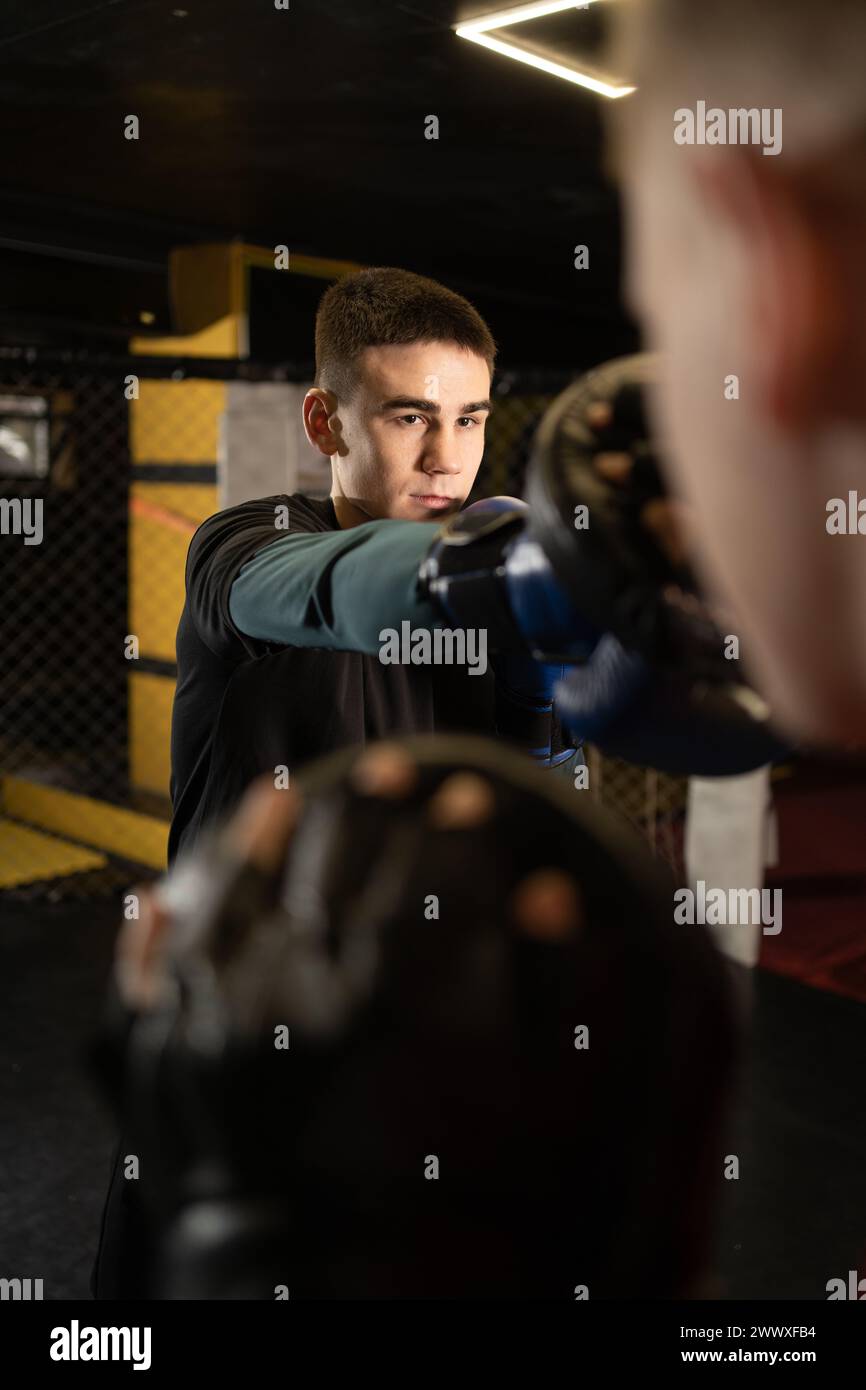 Male boxer punching in boxing training session, delivering strike to ...