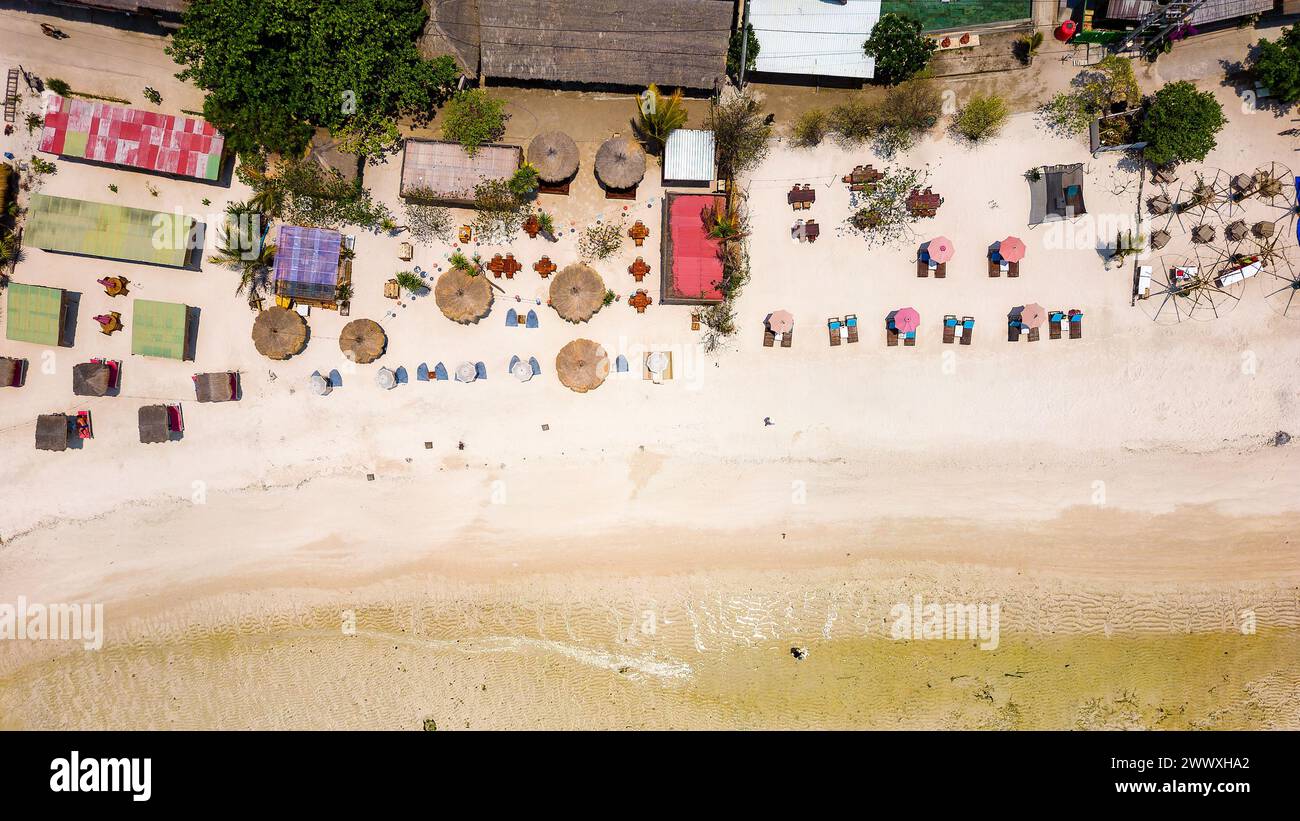 Top down aerial view of various sunshades and resorts along a tropical ...