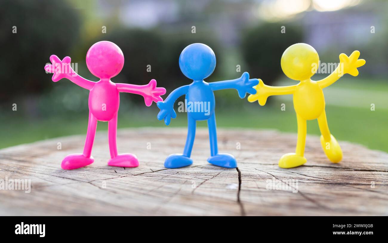 Miniature toy three human figures in yellow, pink and blue. concept of ...