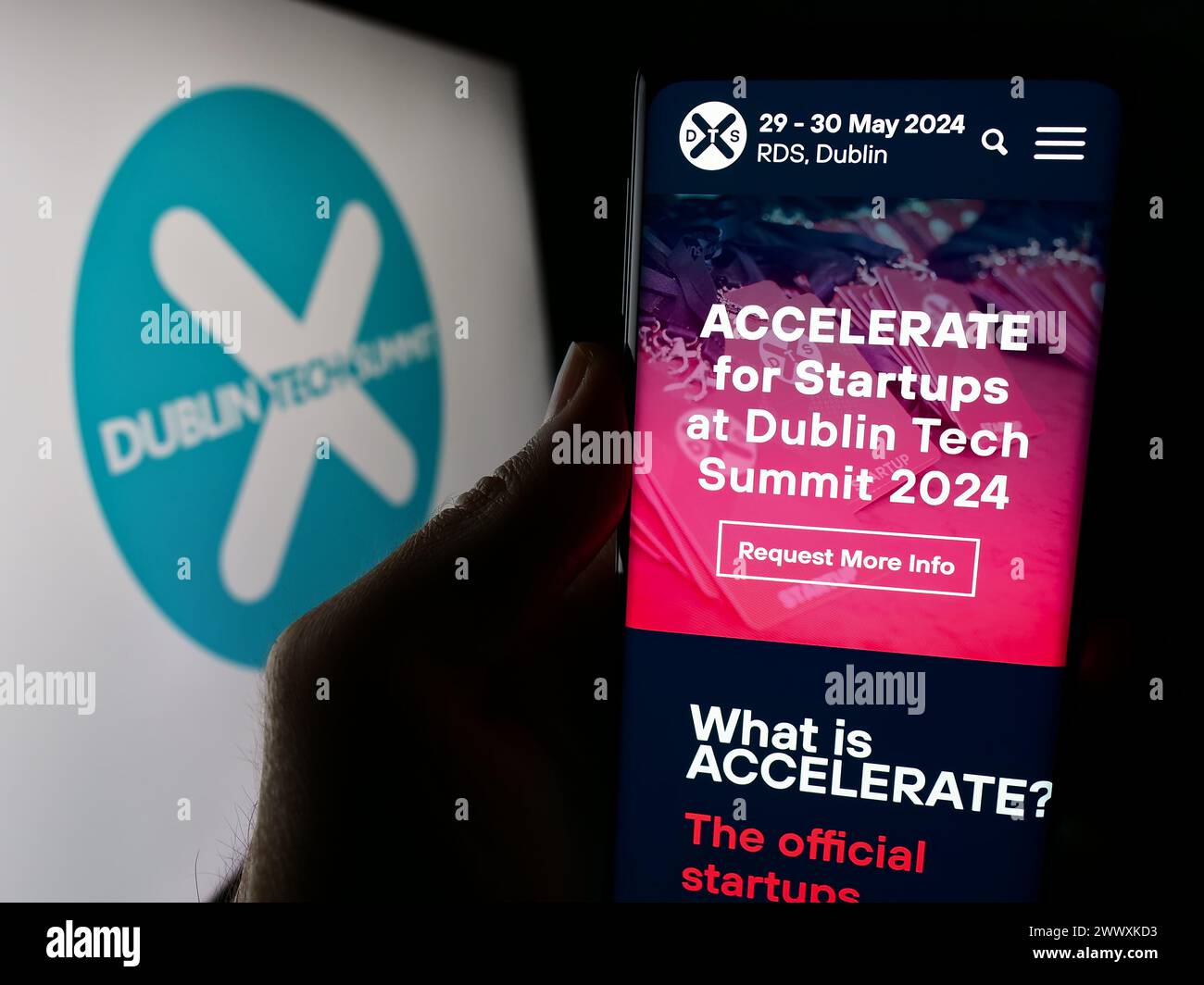 Person holding mobile phone with website of technology conference ...