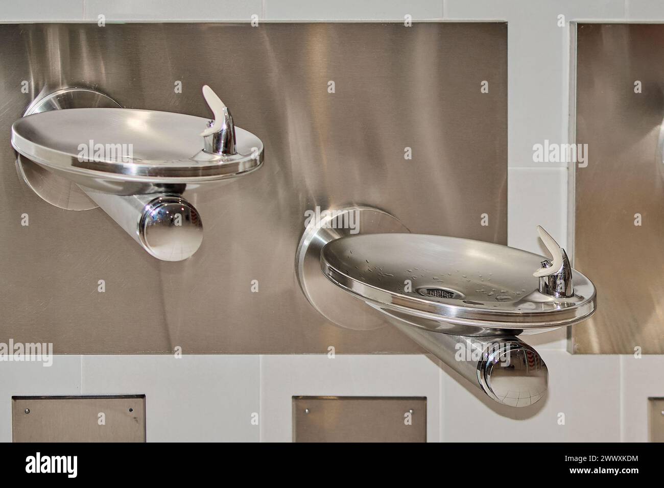 Two stainless steel water fountains mounted on a white wall, ideal for ...