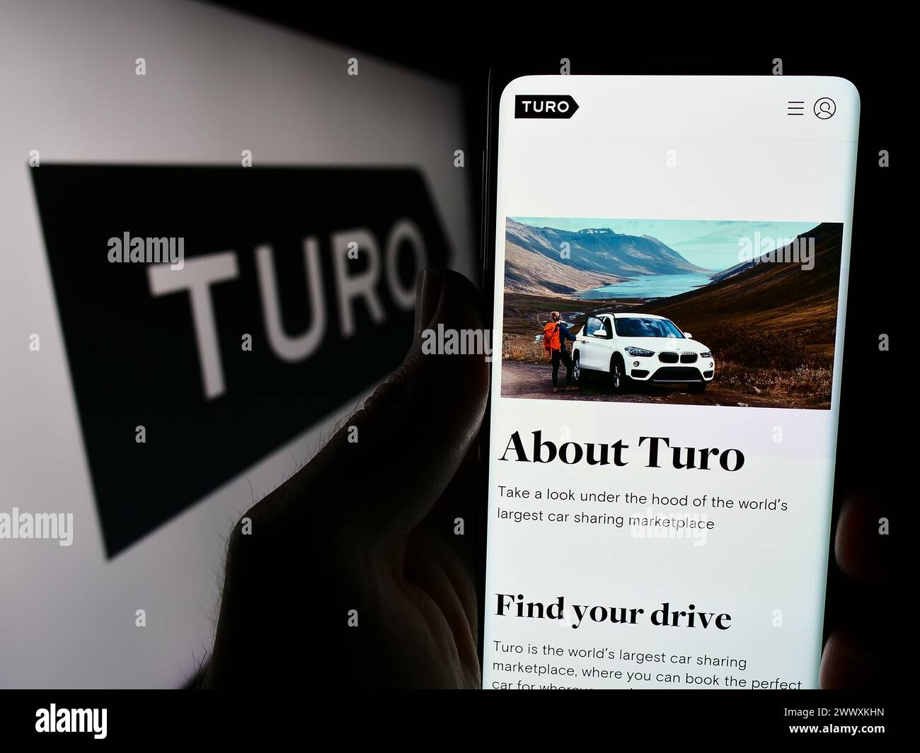 Person holding cellphone with webpage of US peer-to-peer carsharing ...