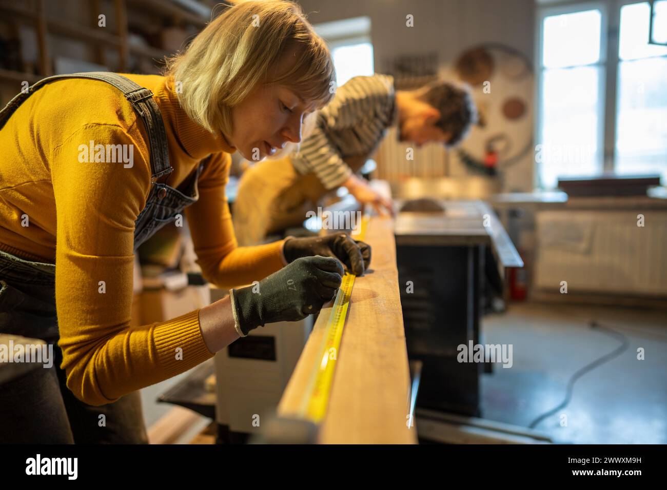 Woman carpenter marking point on plank for sawing in carpentry workshop ...