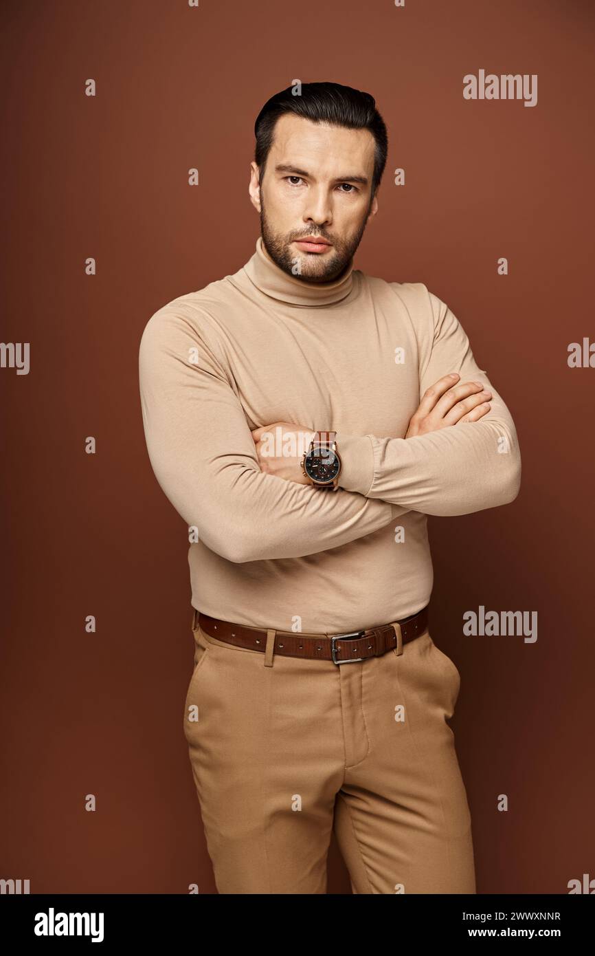 Determined and handsome man in turtleneck posing with crossed arms and ...