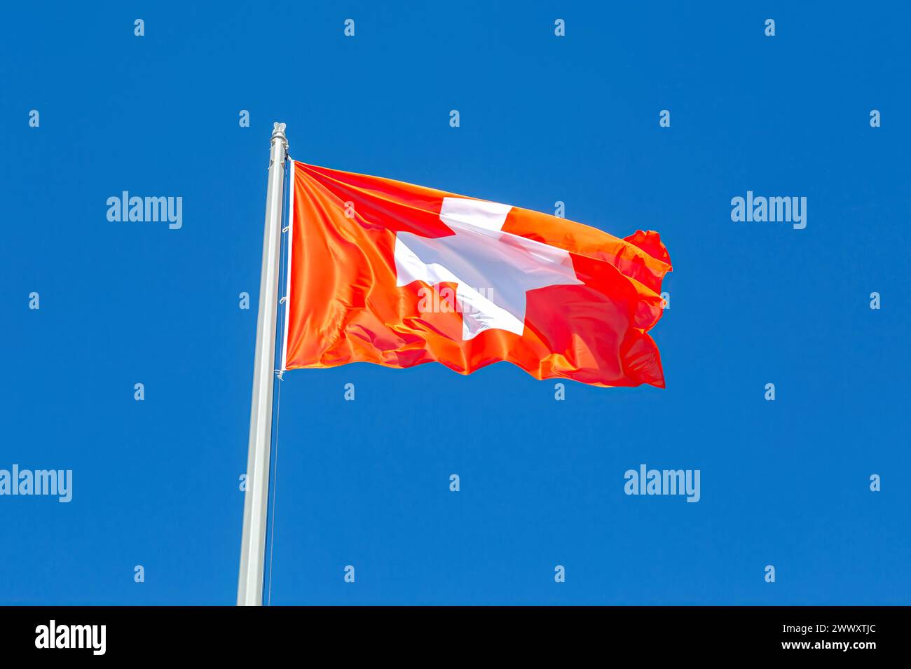 Flag of Switzerland flying in the wind against a blue sky. Switzerland ...