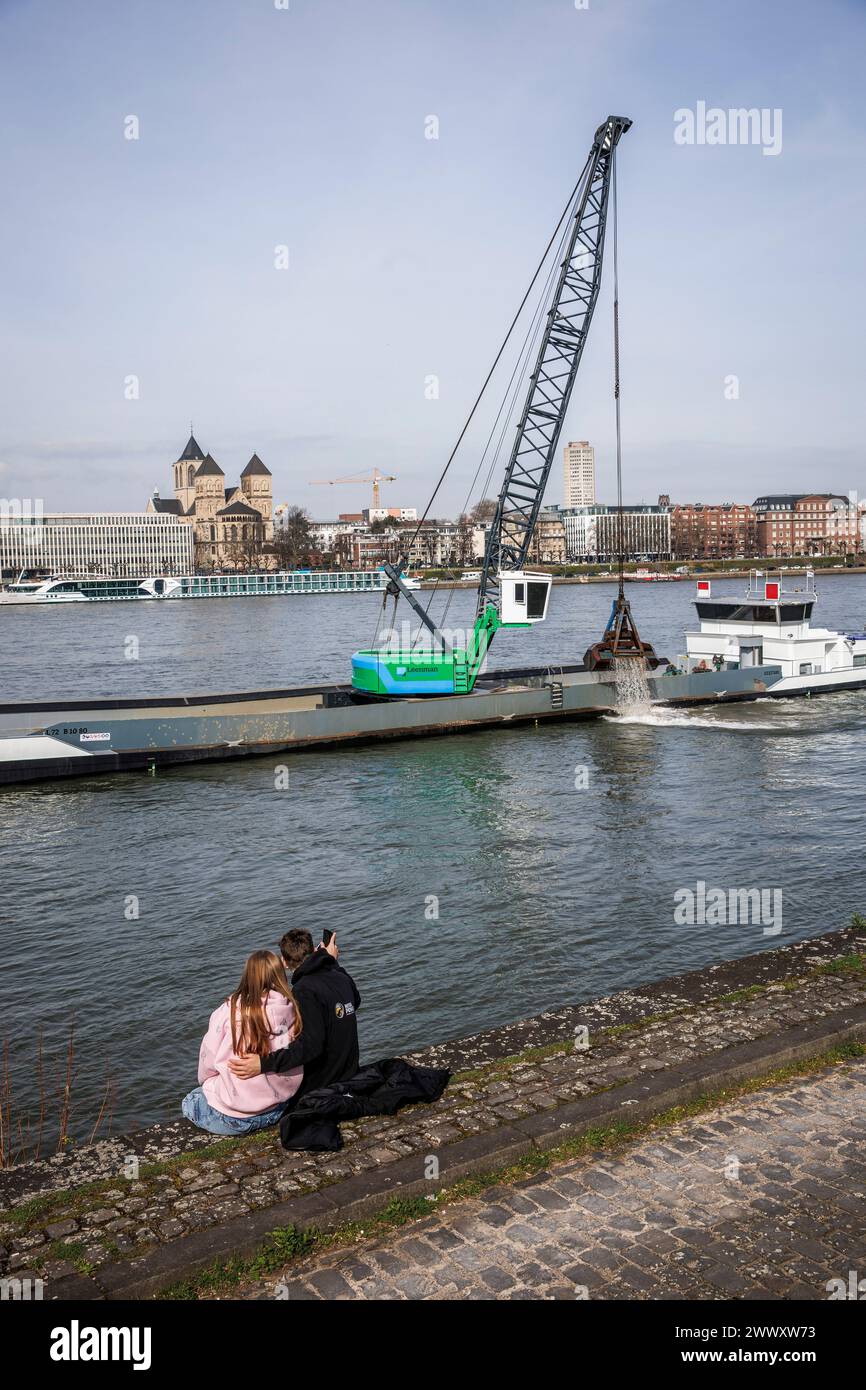 excavator on a ship deepens the riverbed of the river Rhine, couple on ...